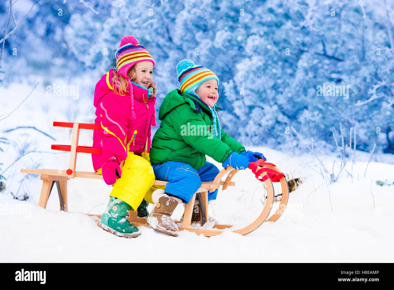 Little girl and boy enjoy a sleigh ride. Child sledding. Toddler kid ...