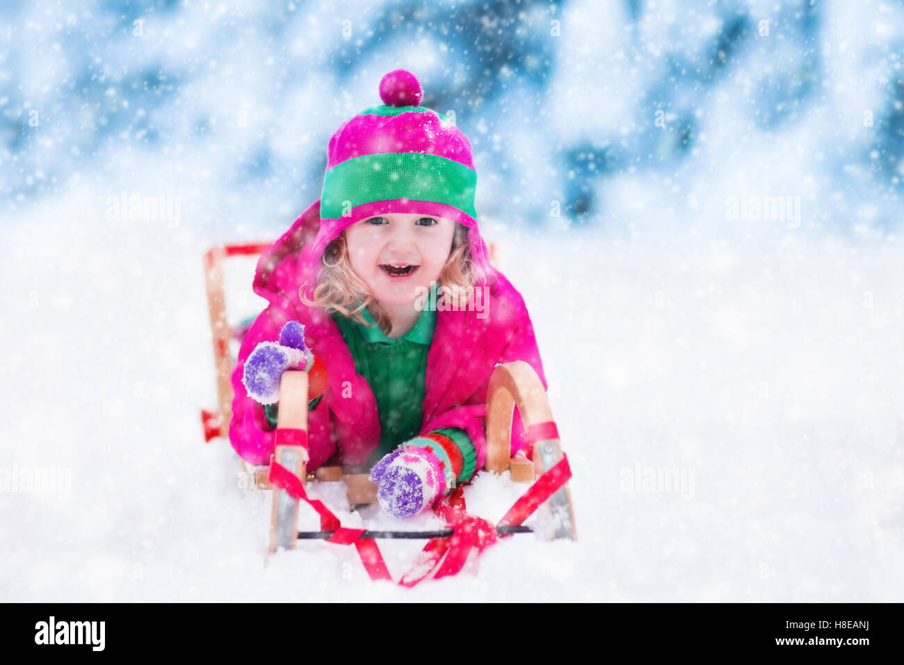 Little girl enjoying a sleigh ride. Child sledding. Toddler kid riding ...