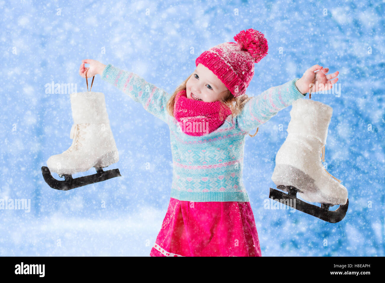 Happy laughing little girl having fun ice skating in snowy park. Winter ...