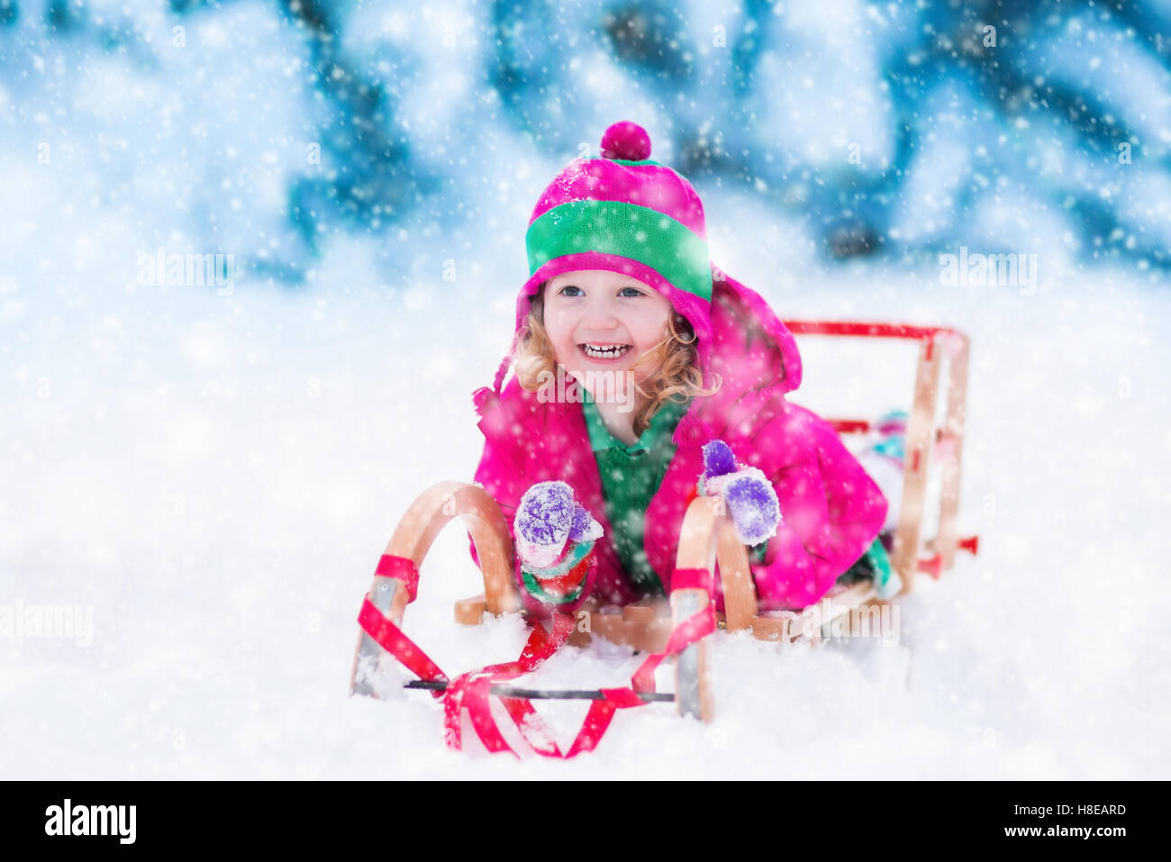 Little girl enjoying a sleigh ride. Child sledding. Toddler kid riding ...
