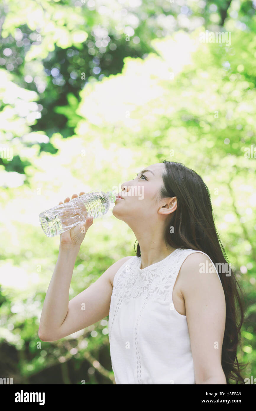 Young Japanese woman drinking water in a city park Stock Photo - Alamy