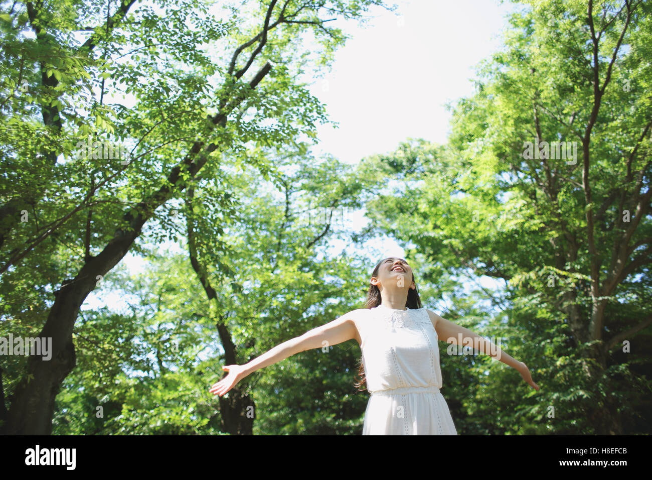 Young Japanese woman surrounded by green in a city park Stock Photo - Alamy