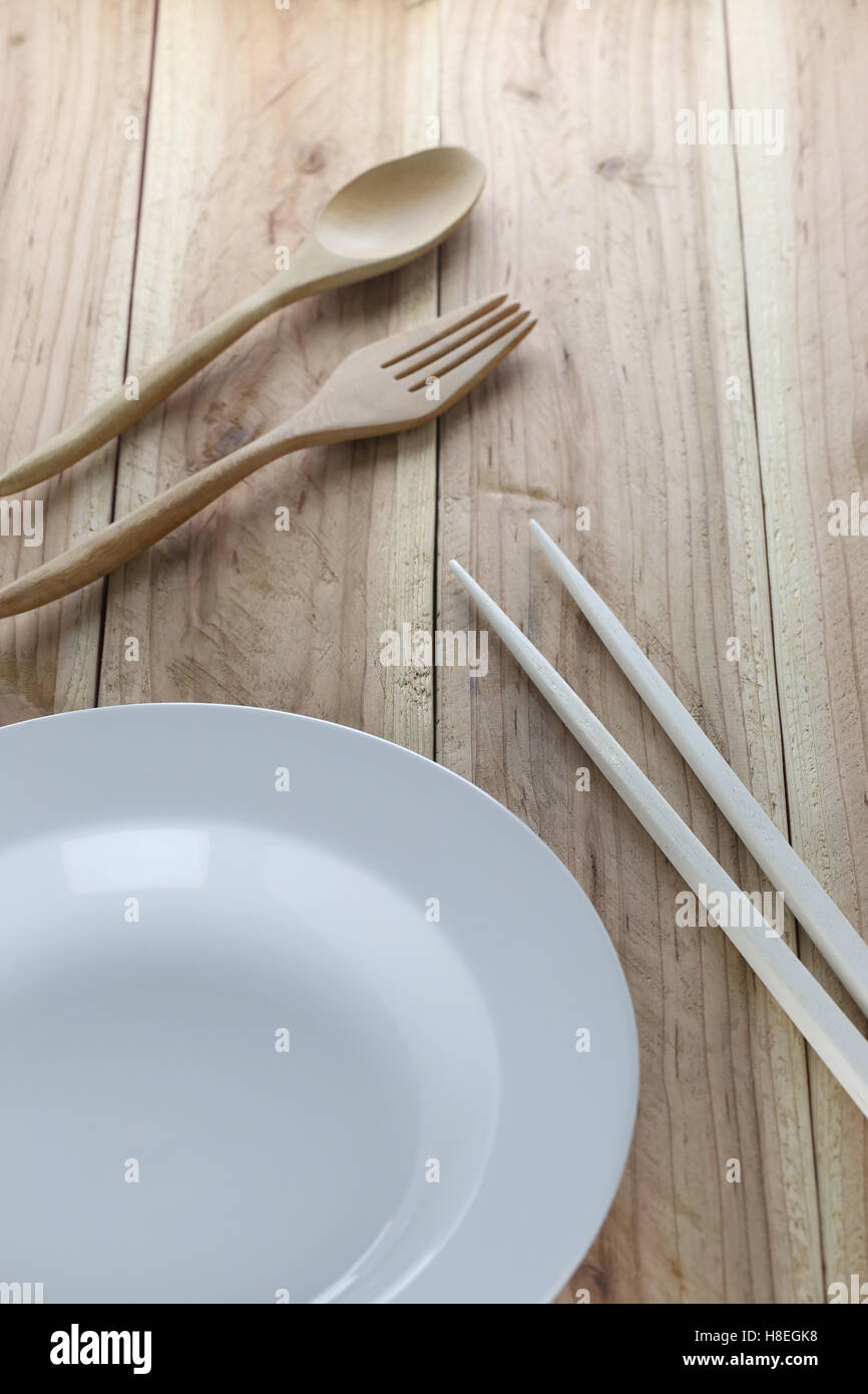 White plate,wooden spoon and chopsticks on wooden floor background ...