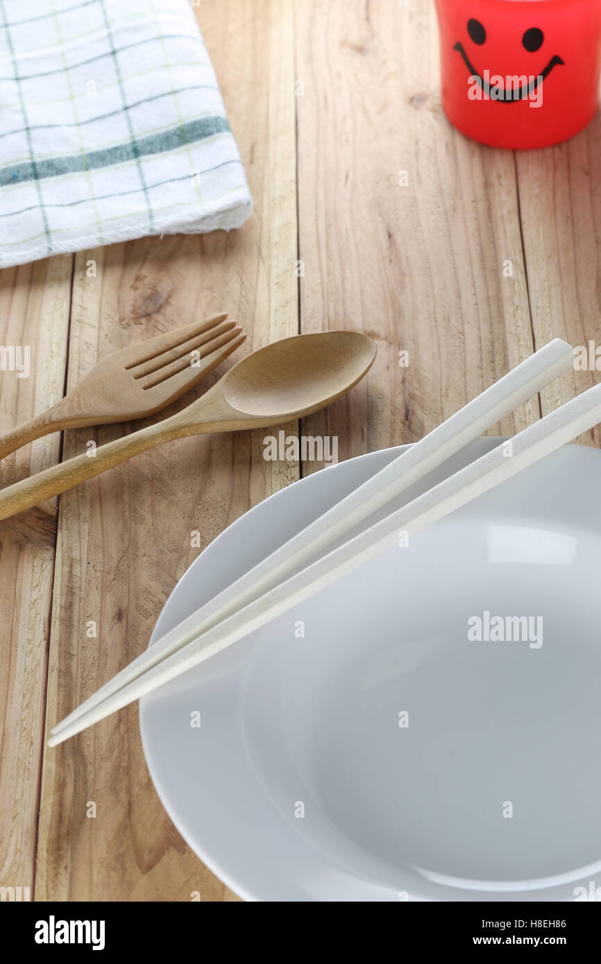 White plate,wooden spoon and chopsticks on wooden floor background ...