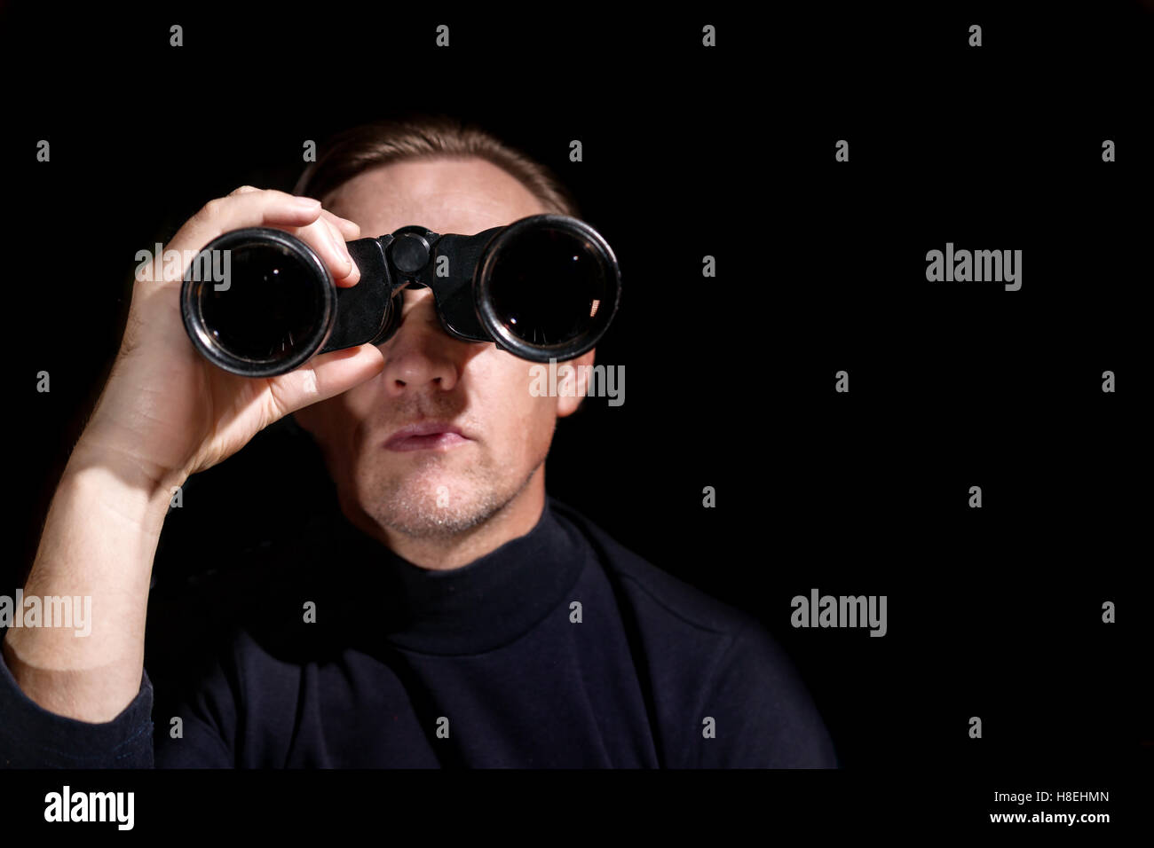 man looking through binoculars on a dark background Stock Photo - Alamy