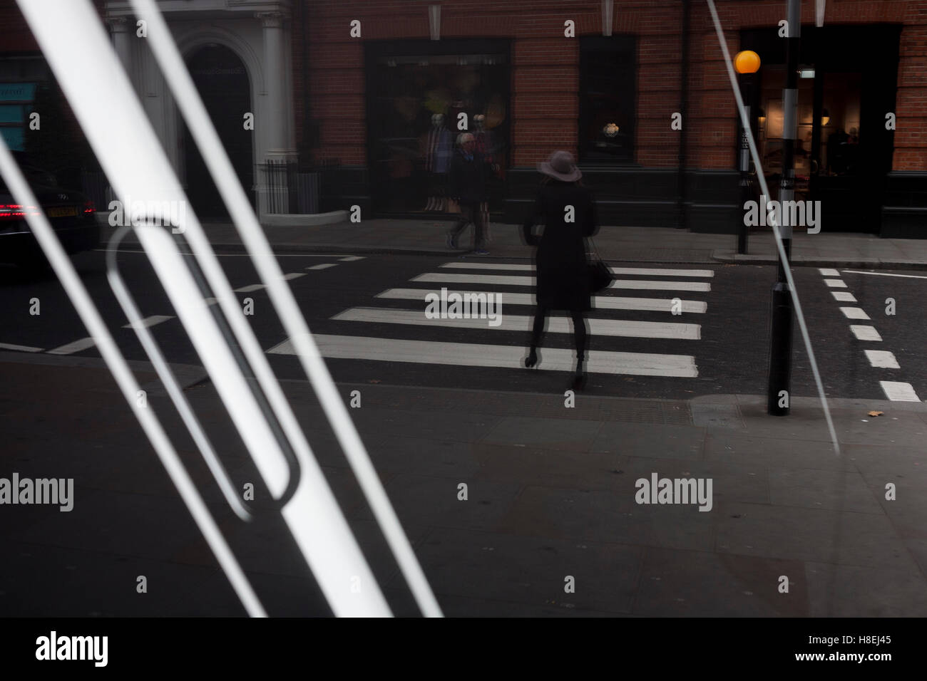 A lady pedestrian crosses a zebra crossing with the stripes of an Apple ...