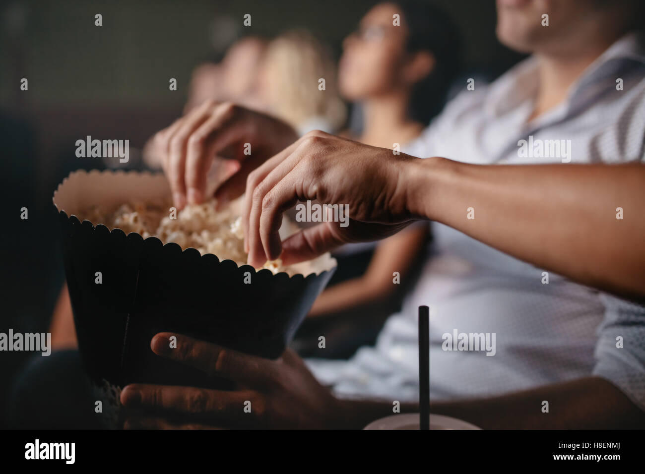 Close up shot of young people eating popcorn in movie theater, focus on ...