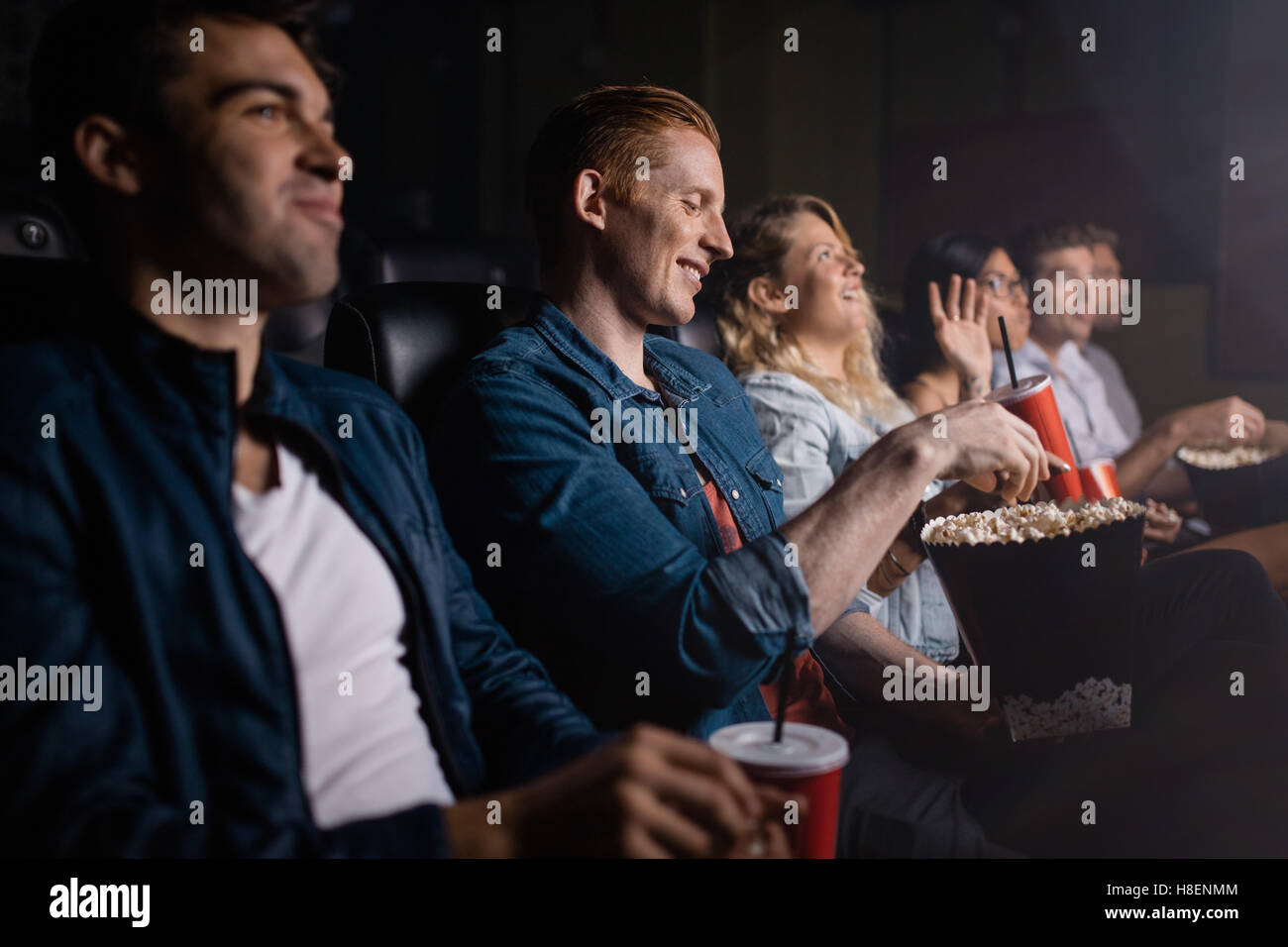 Young man with friends watching movie in cinema. Group of people in ...