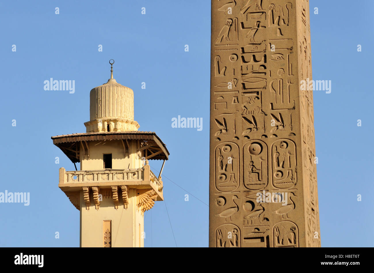 Close-up of red granite obelisk and mosque minaret at Luxor Temple of ...