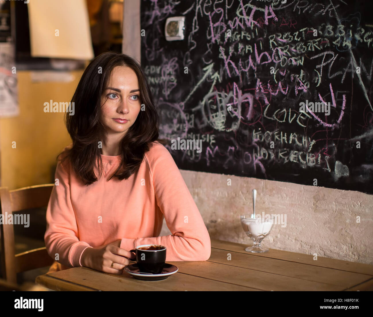 Young pensive woman sitting in a cafe Stock Photo - Alamy