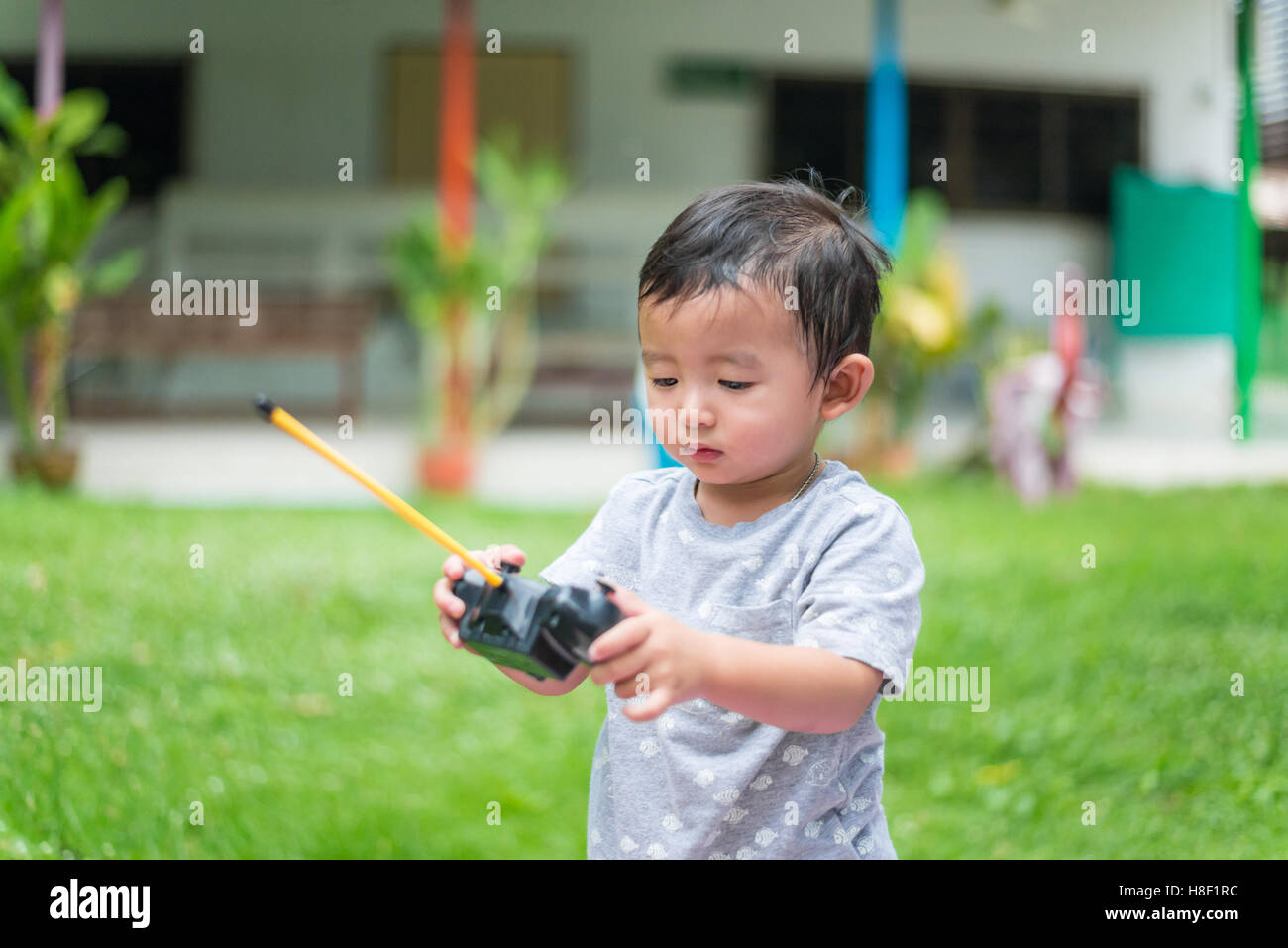 Little Asian kid holding a radio remote control (controlling handset ...