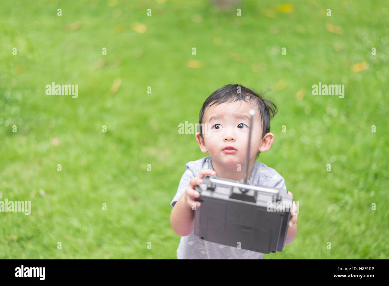 Little Asian kid holding a radio remote control (controlling handset ...