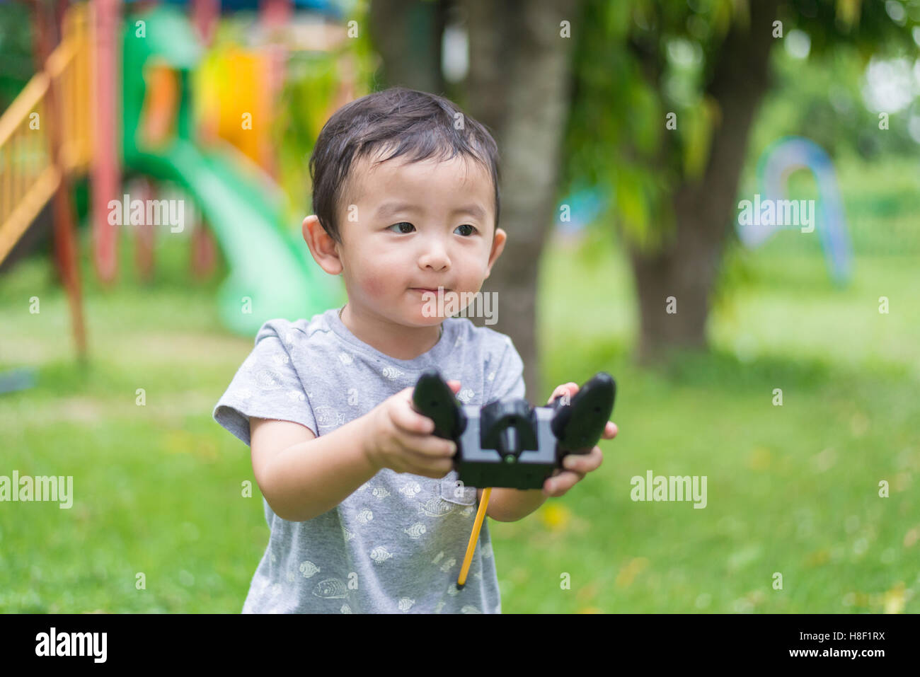 Little Asian kid holding a radio remote control (controlling handset ...