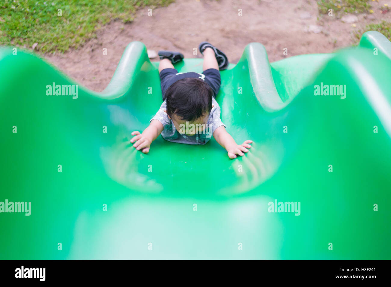 Little Asian kid climbing up the slide at the playground under the ...