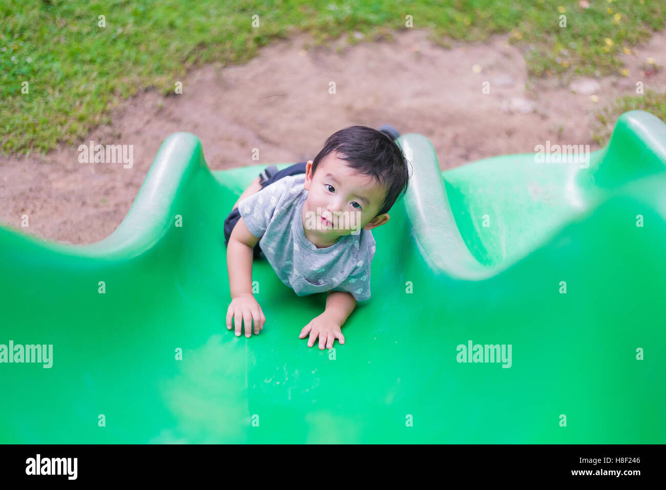 Little Asian kid climbing up the slide at the playground under the ...