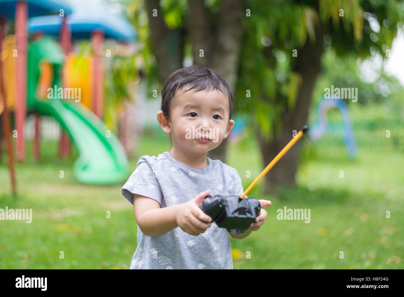 Little Asian kid holding a radio remote control (controlling handset ...