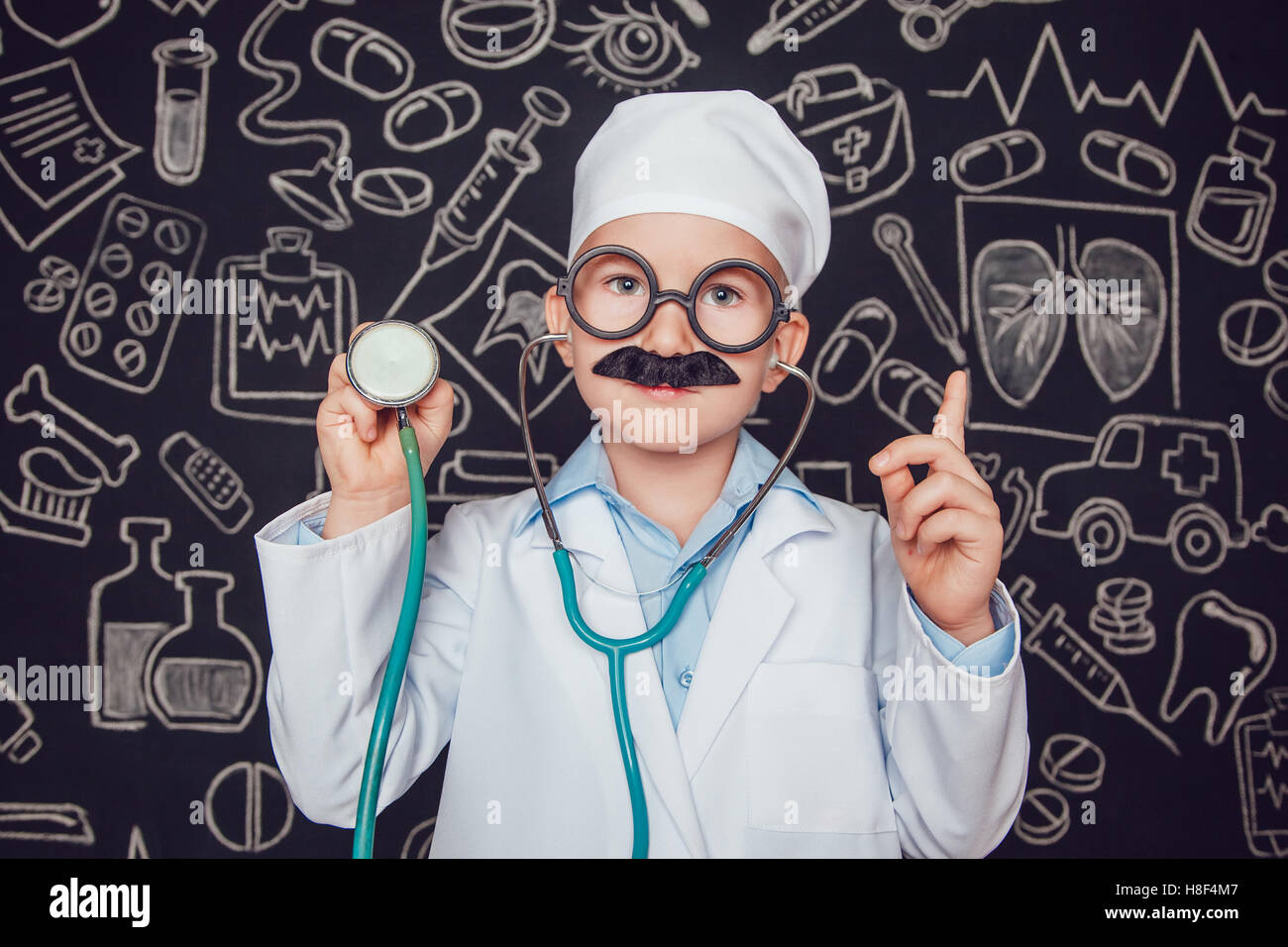 Little boy in doctor costume holding sthetoscope on dark background ...
