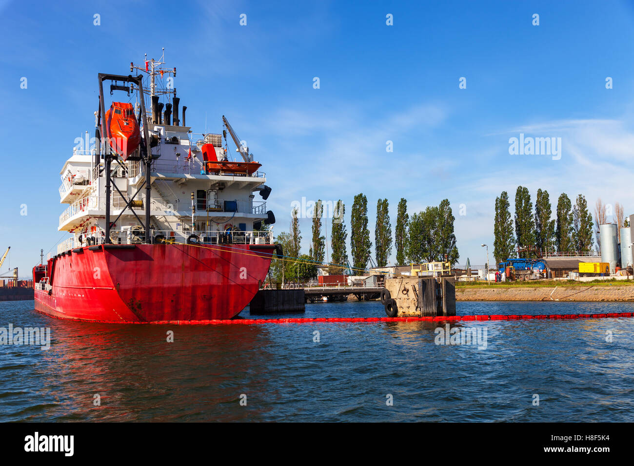 Cargo ship moored on port surrounded by oil spill barrier Stock Photo ...
