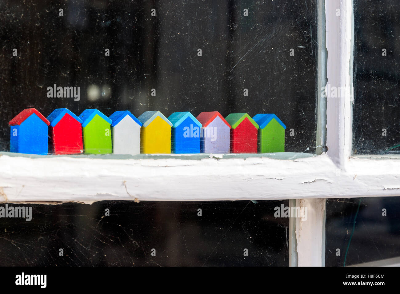 Row of little colourful beach hut wooden ornaments sitting on window ...