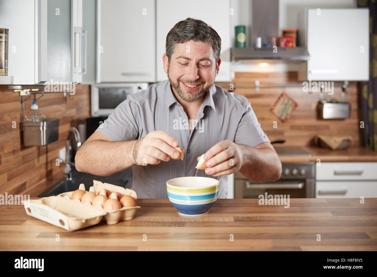 Caucasian man cracking egg in a bowl in the kitchen for cooking Stock ...