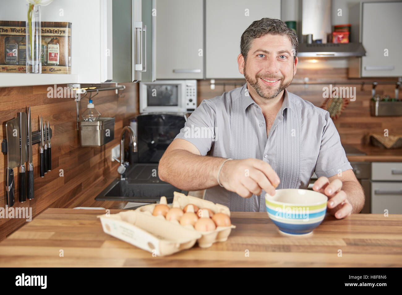 Caucasian man cracking egg in a bowl in the kitchen for cooking Stock ...