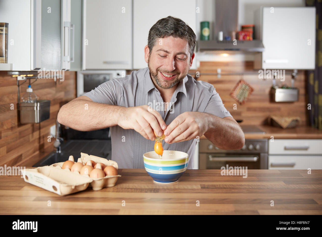 Caucasian man cracking egg in a bowl in the kitchen for cooking Stock ...