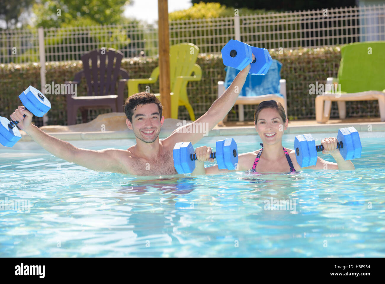 Man and woman in pool holding swimming aids Stock Photo - Alamy