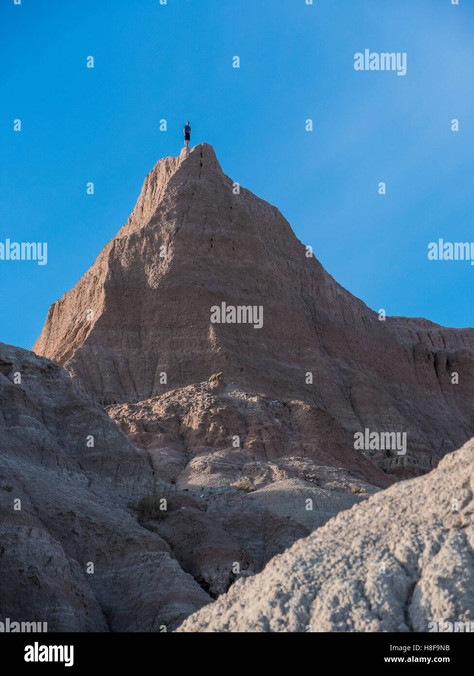 Man stands atop a pinnacle, Saddle Pass Trail, Badlands National Park ...