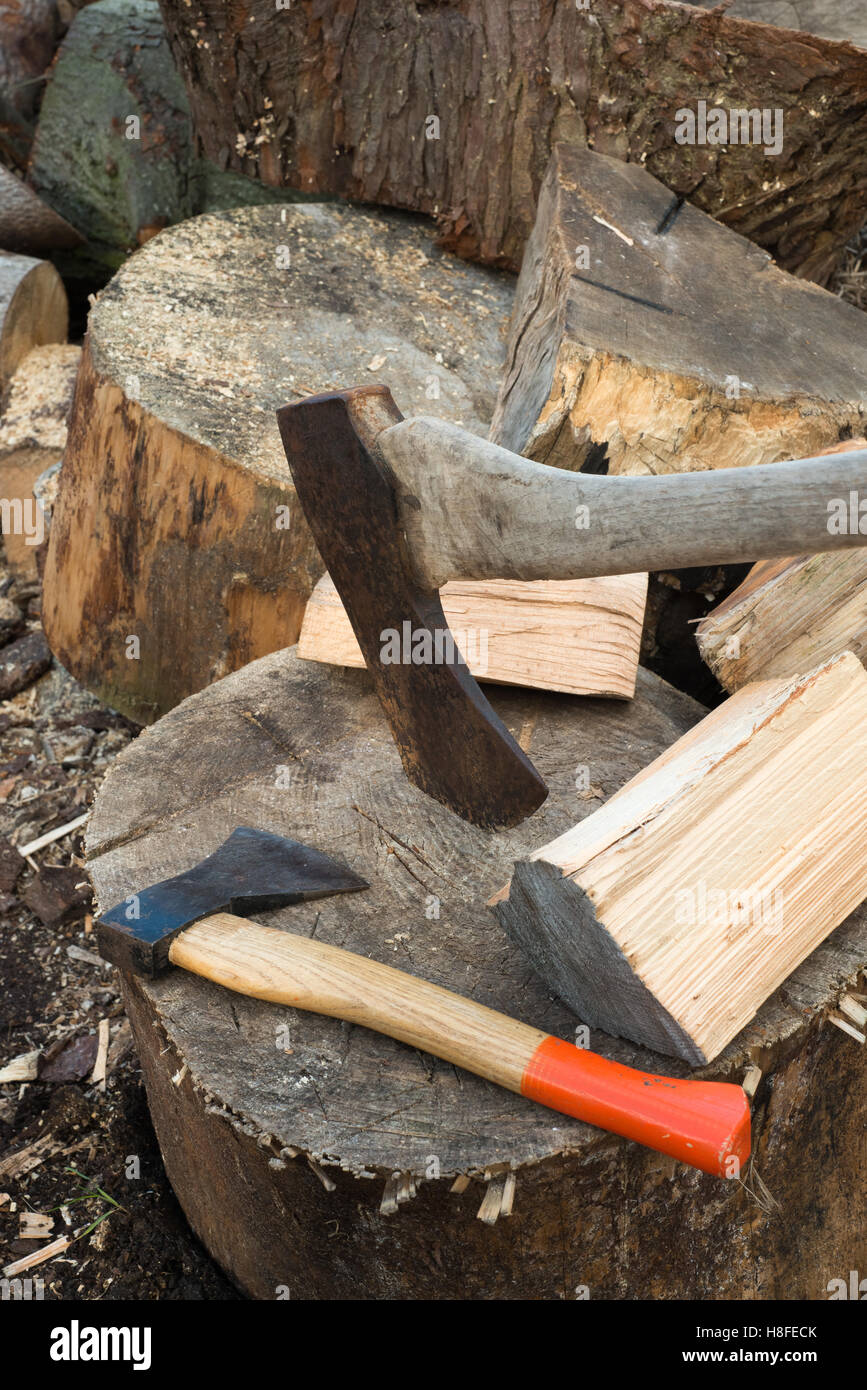 Pair of hatchets of different sizes on a log alongside chunks of ...