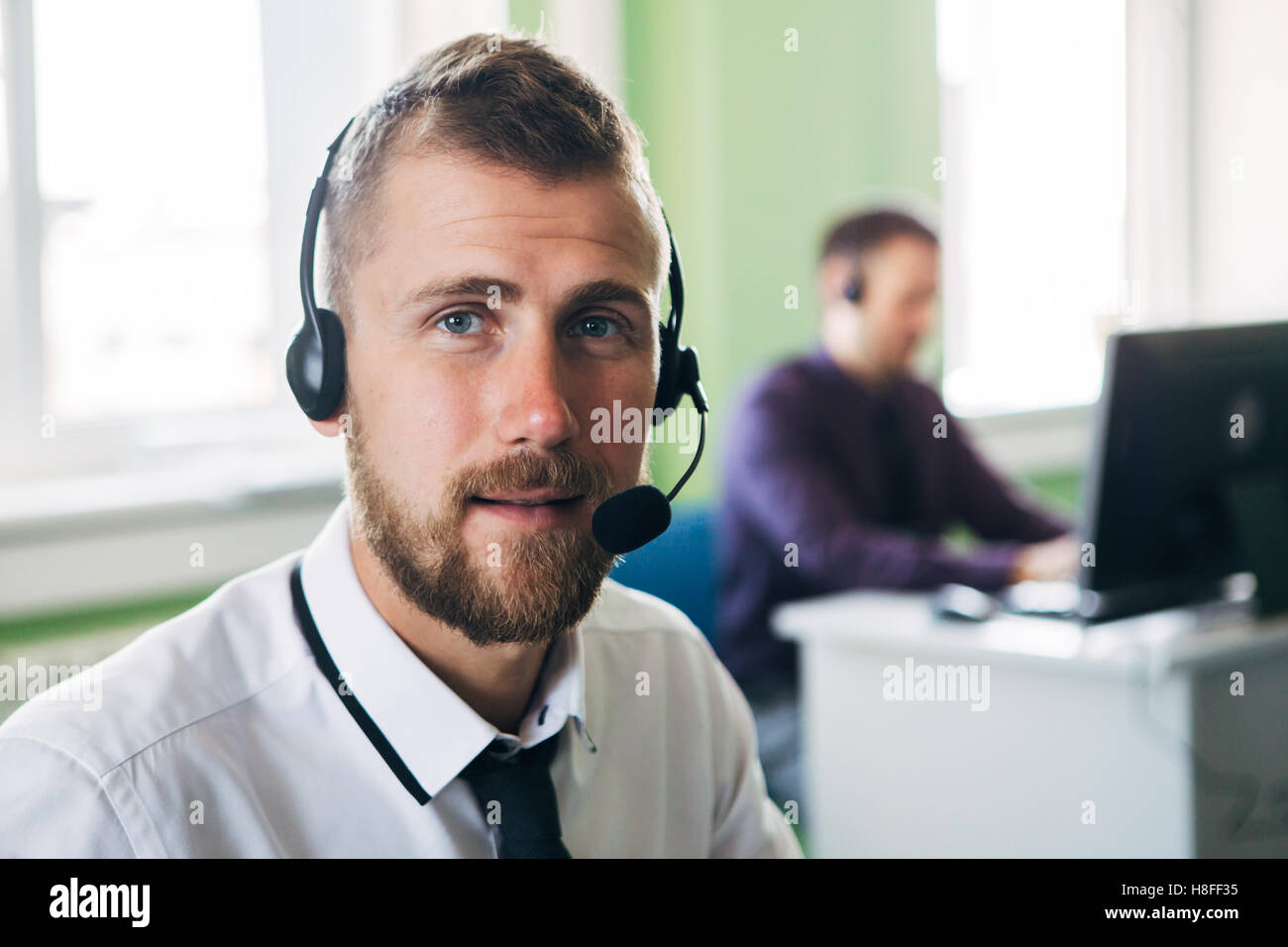 Businessman in the office on the phone with headset, looking camera ...