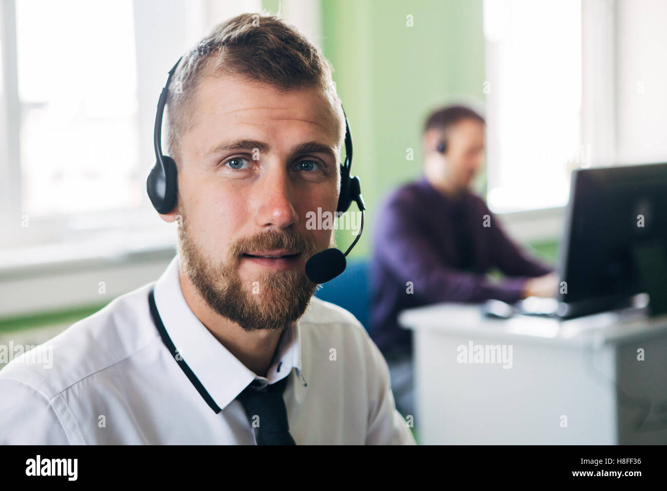 Businessman in the office on the phone with headset, looking camera ...