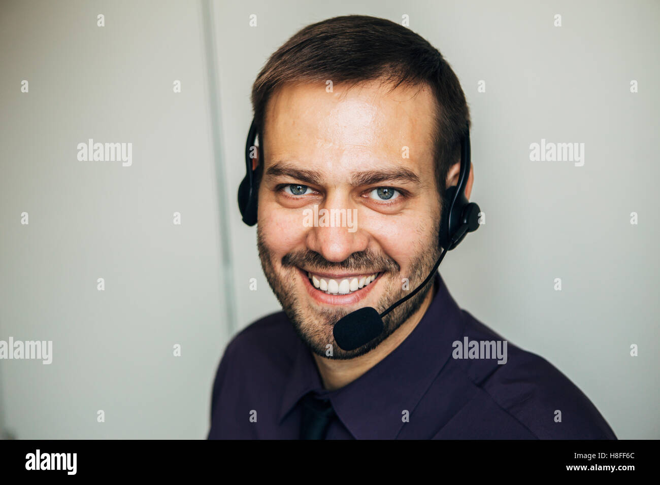 Portrait of handsome young male operator in headset looking at camera ...