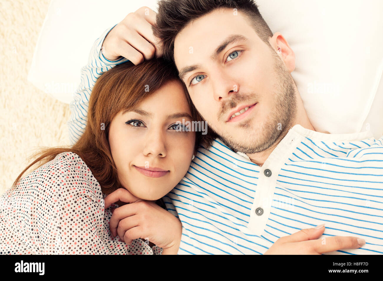 Happy Young Couple laying on bed Stock Photo - Alamy