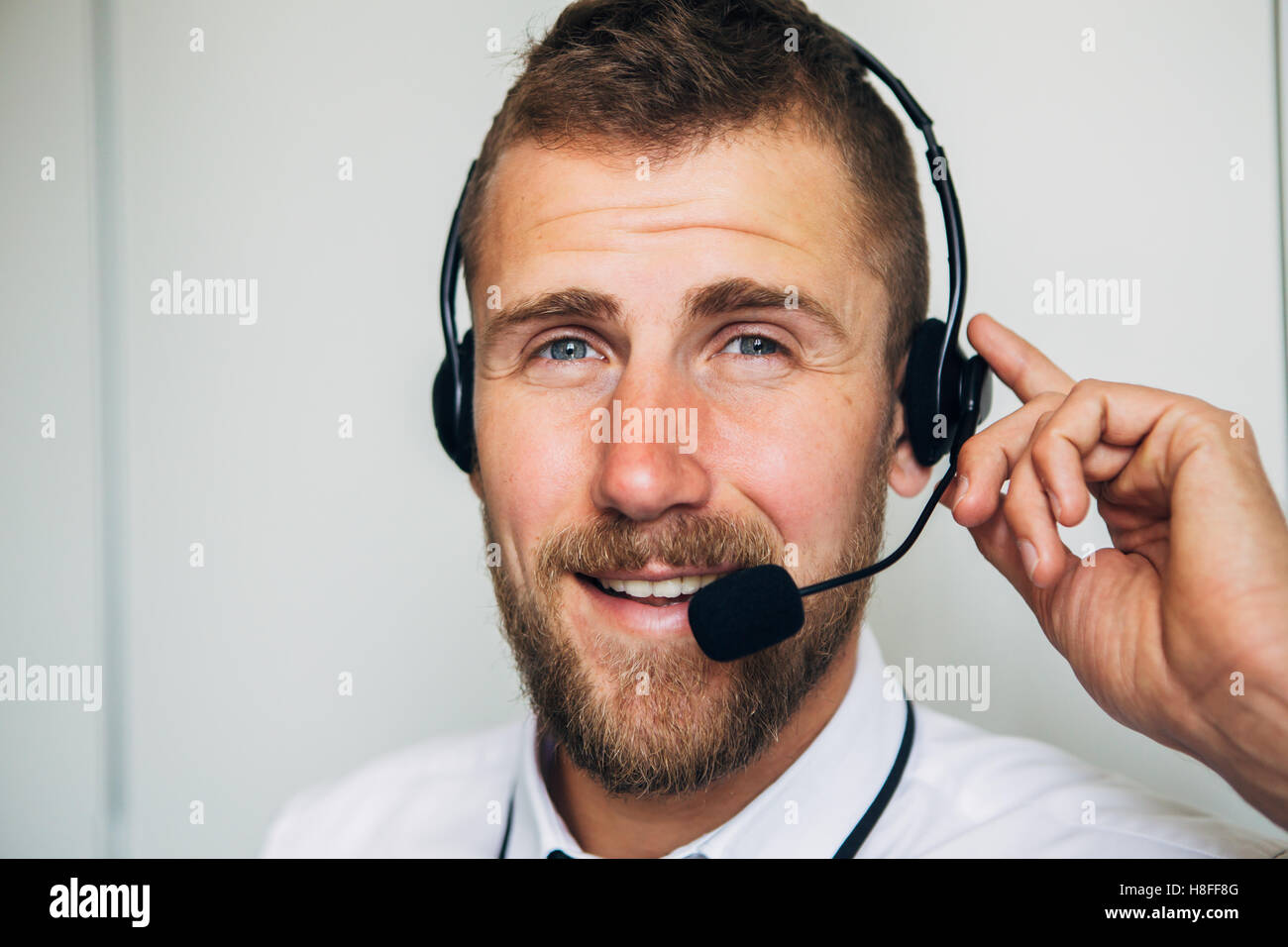 Portrait of handsome young male operator in headset looking at camera ...