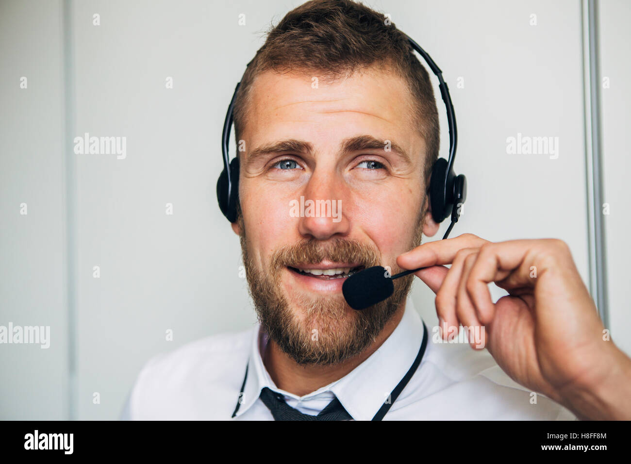 Portrait of handsome young male operator in headset looking at camera ...