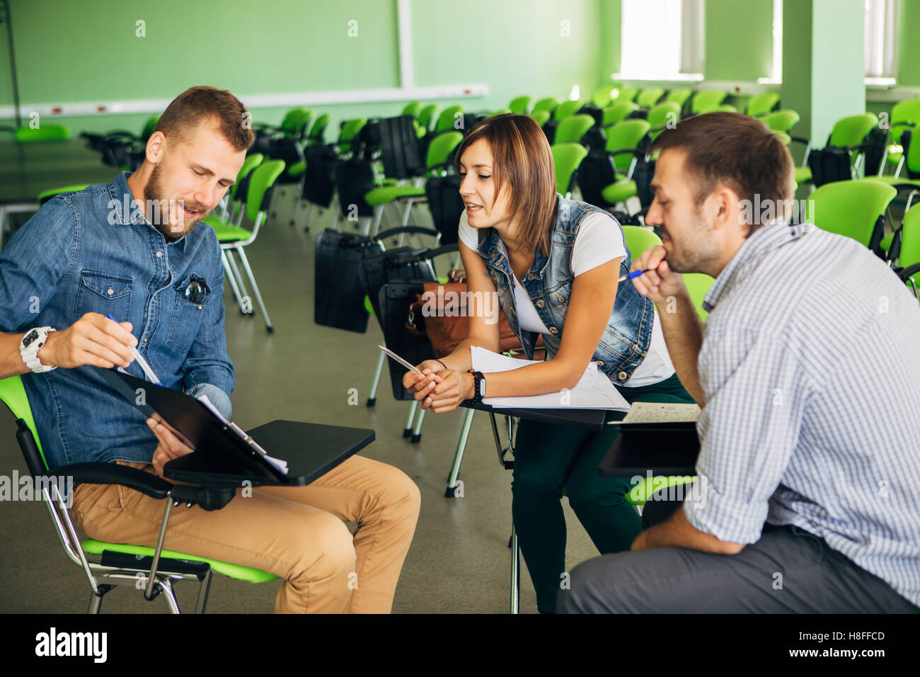 people sitting in the class by the table and listening the presentation ...