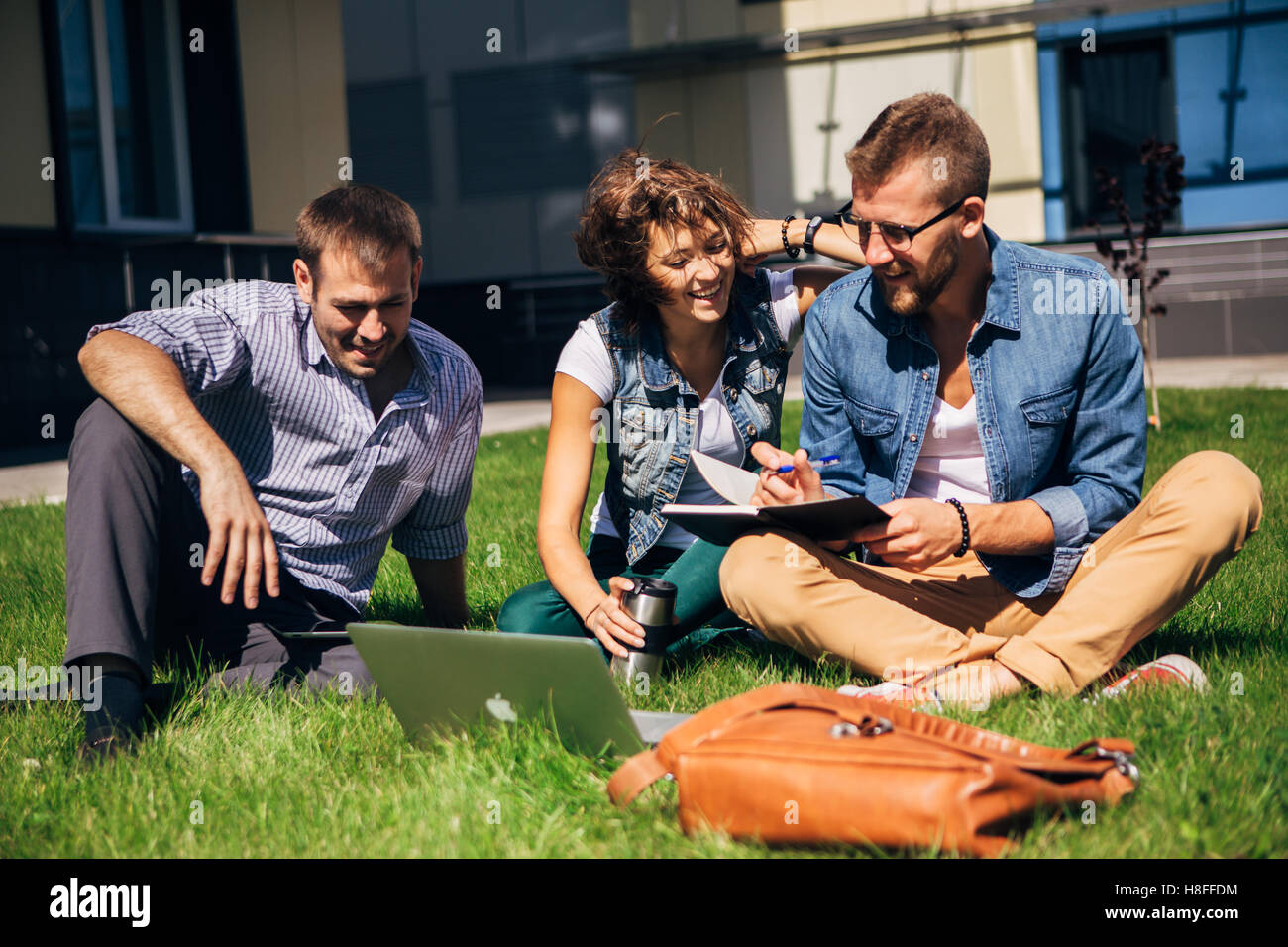 three students sitting on lawn Stock Photo - Alamy