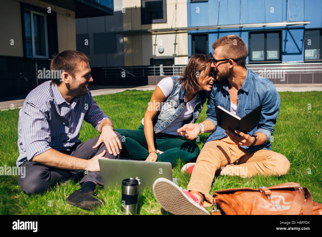 three students sitting on lawn Stock Photo - Alamy