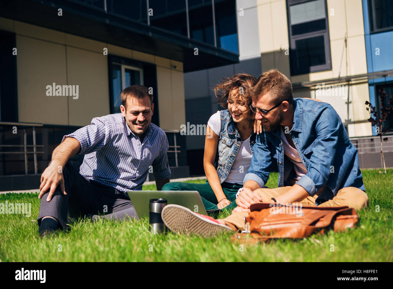 three happy students sitting on lawn Stock Photo - Alamy