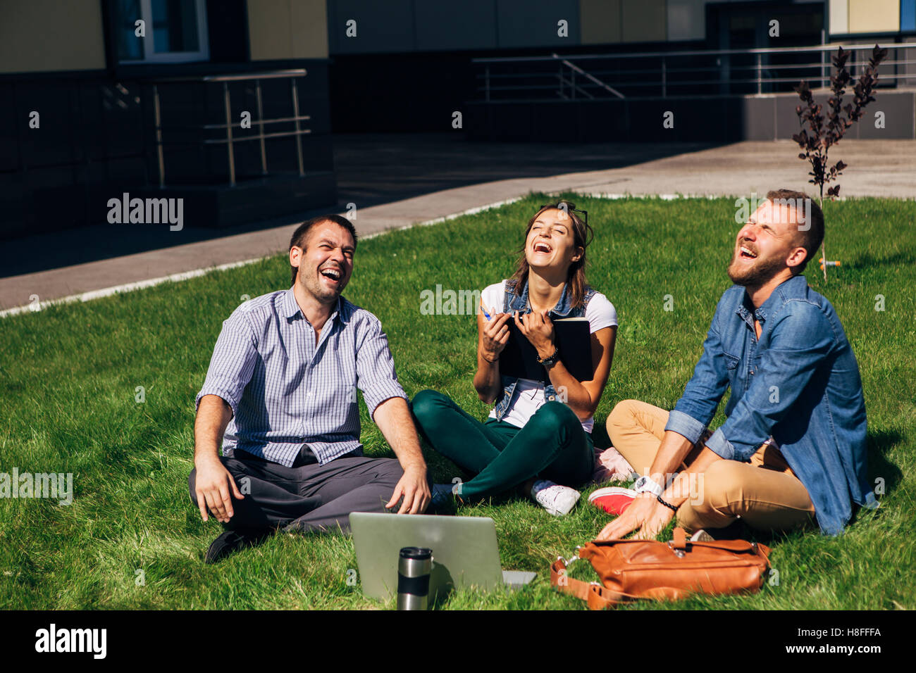 three students sit on the lawn and going to lessons Stock Photo - Alamy