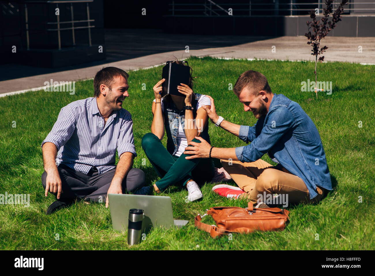three students sit on the lawn and going to lessons Stock Photo - Alamy
