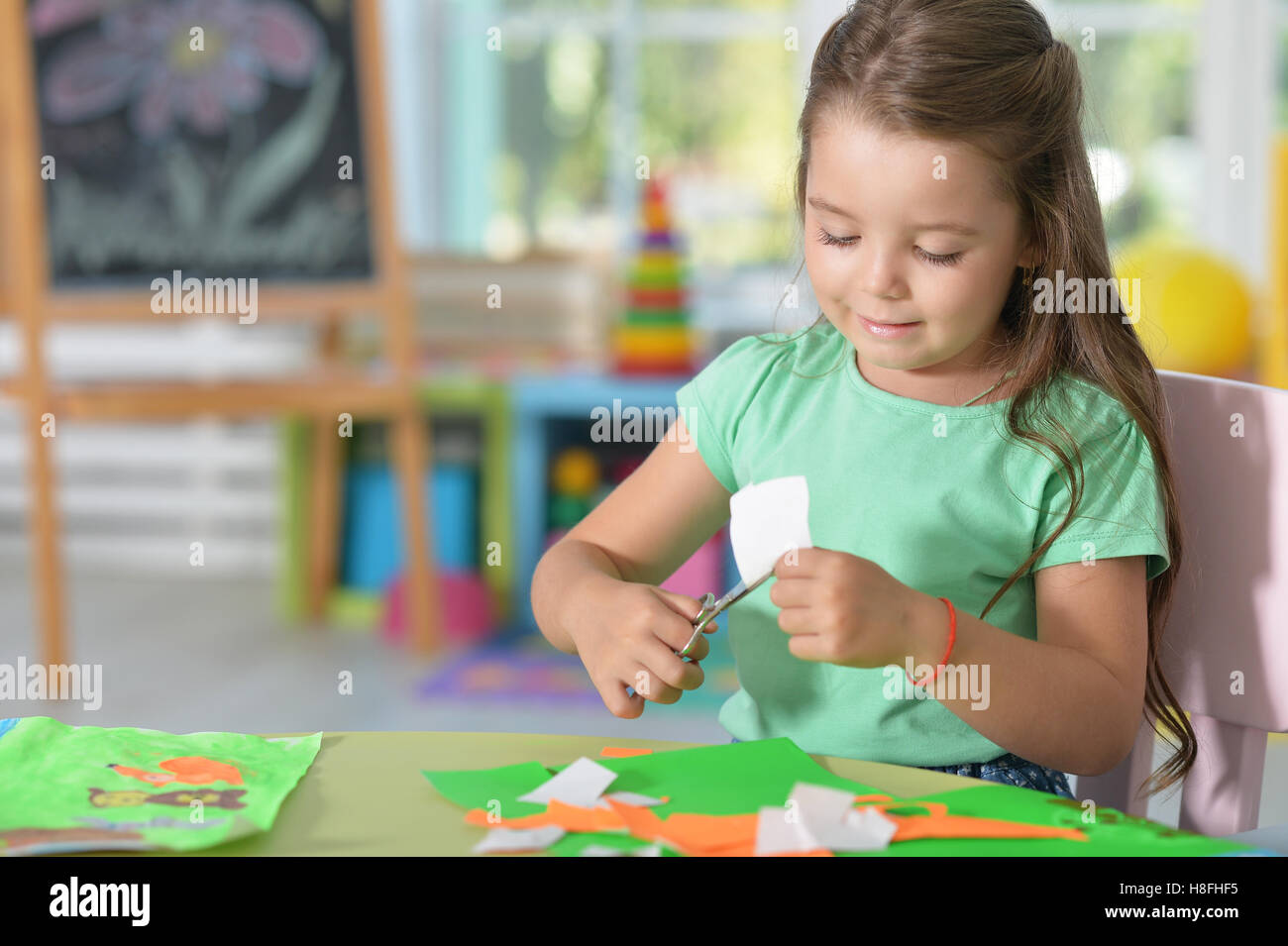 Llittle girl is cutting color paper Stock Photo - Alamy