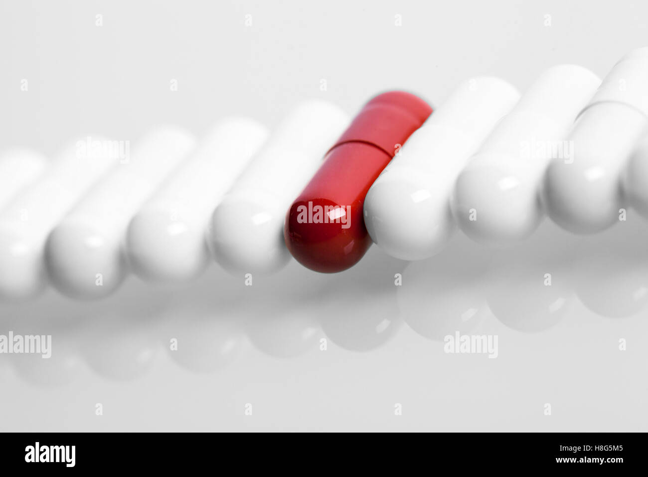 White capsules and one red in line. Studio shot Stock Photo - Alamy