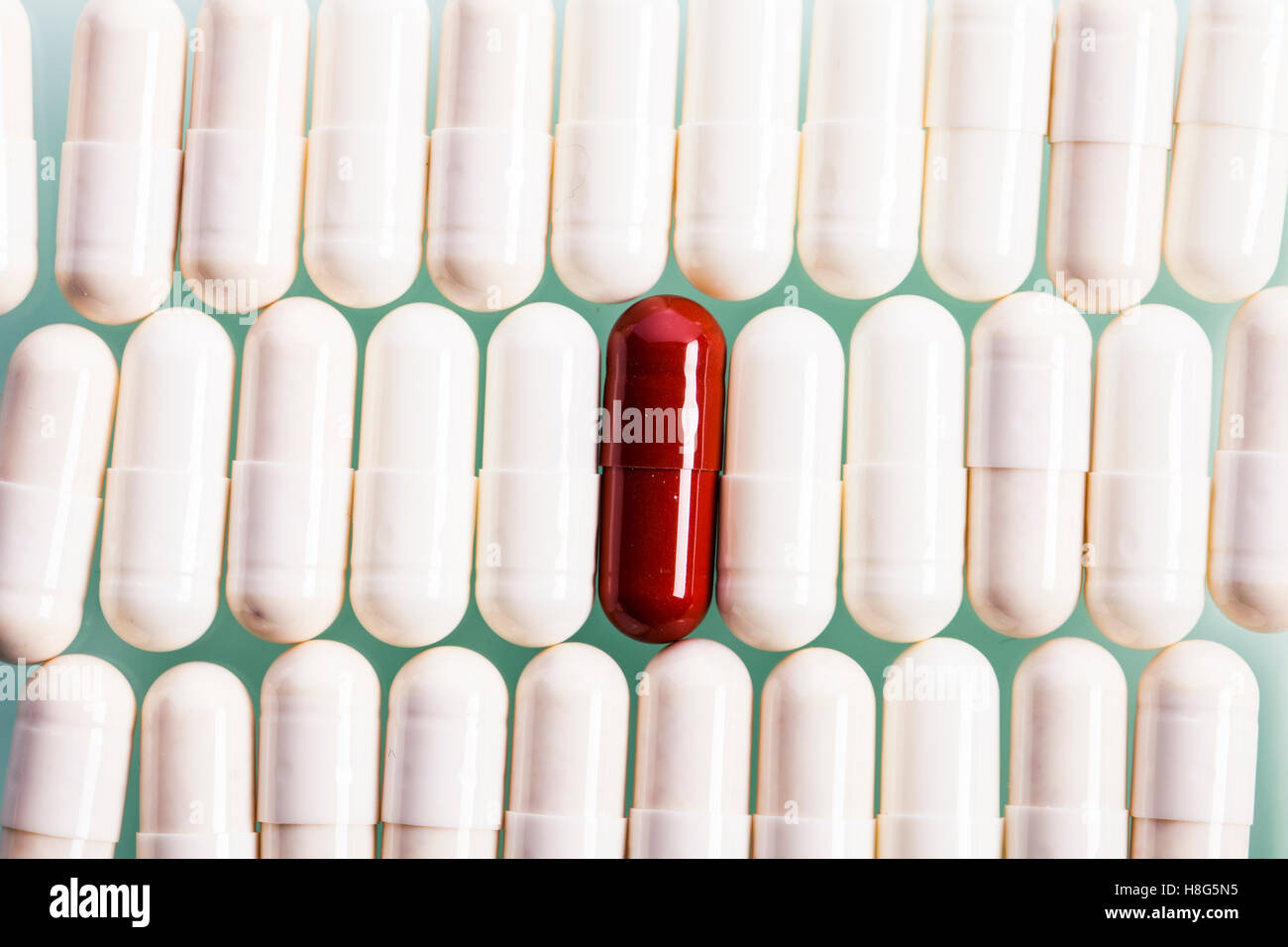 White capsules and one red in line. Studio shot Stock Photo - Alamy