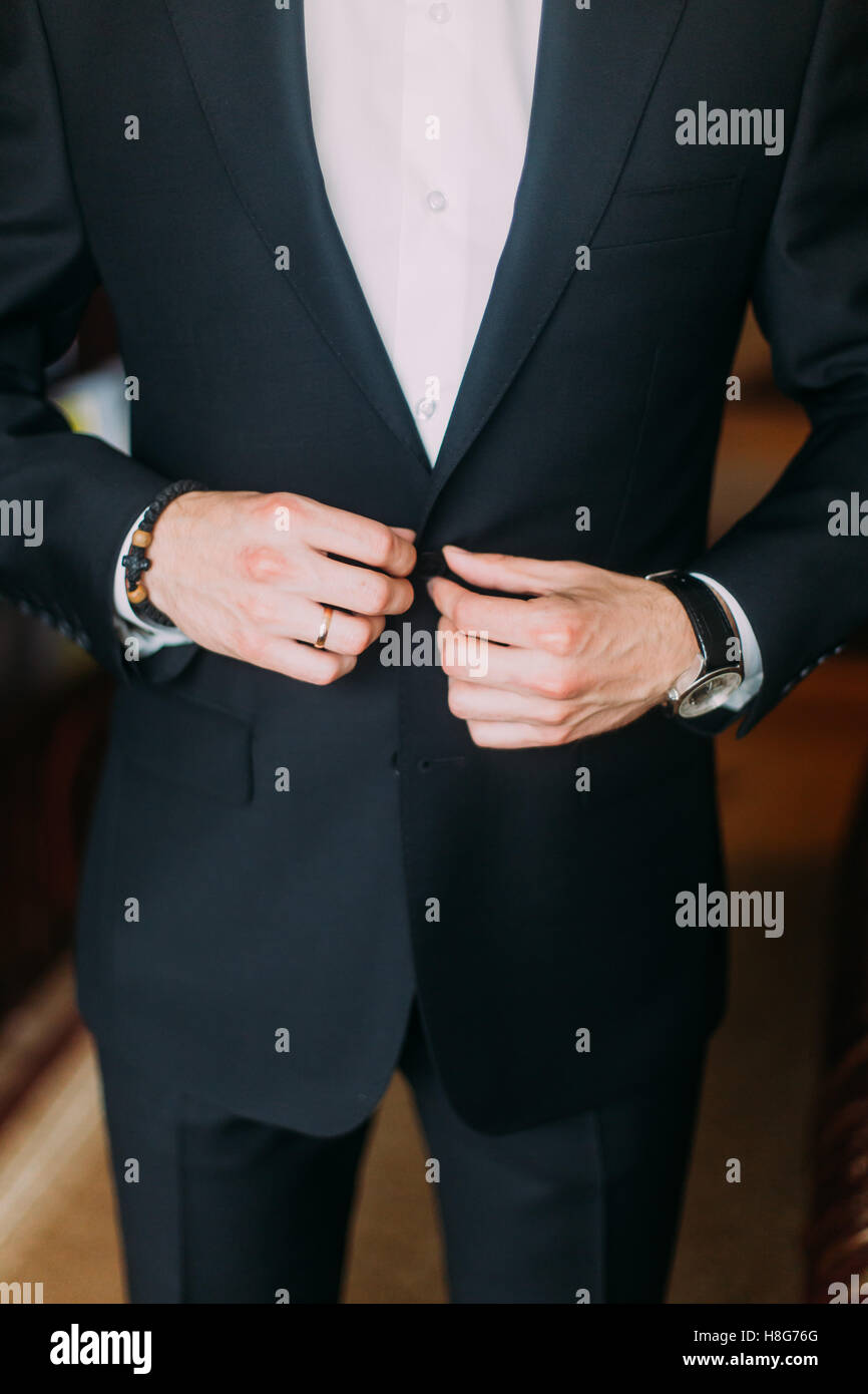 Stylish man dressing in elegant black suit indoors Stock Photo - Alamy