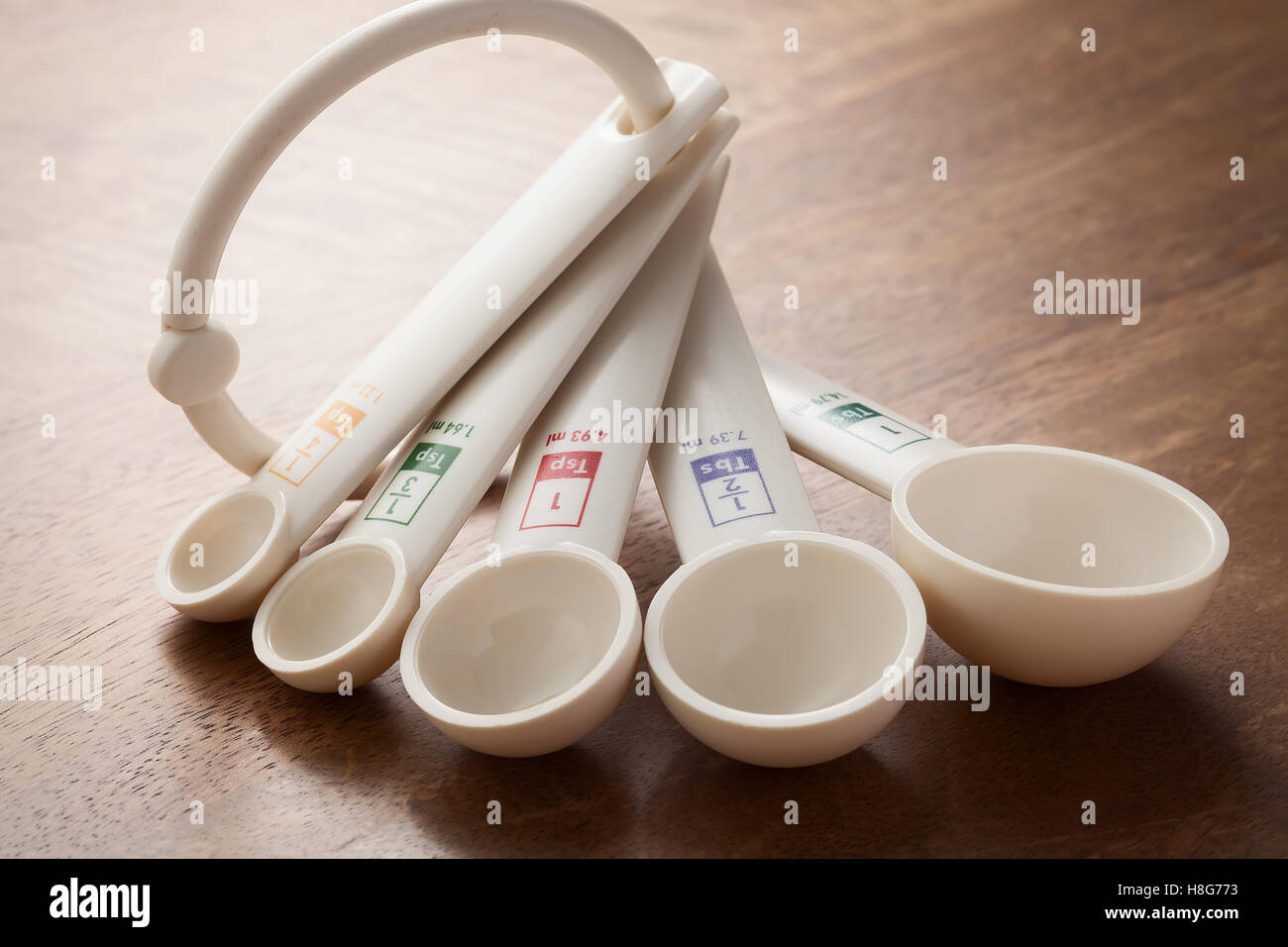measuring spoons in varying sizes on wooden background kitchen object ...