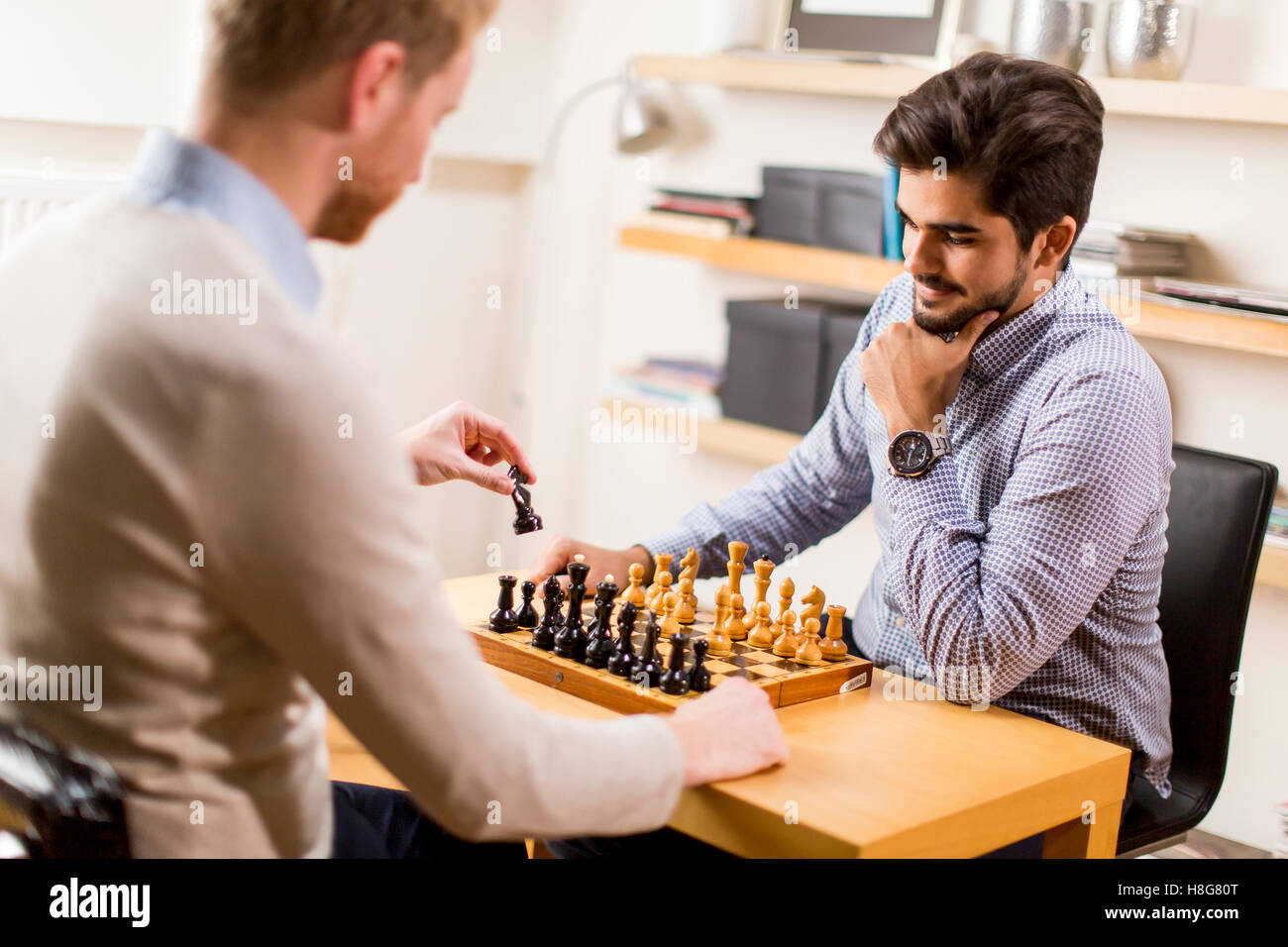 Two young men playing chess in room Stock Photo - Alamy