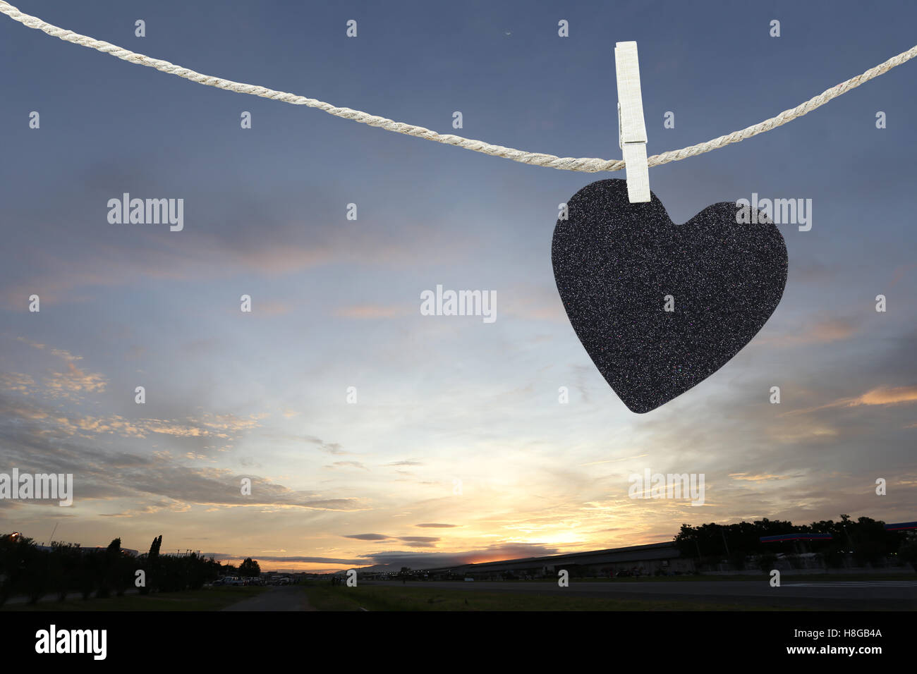 Black Heart hung on hemp rope on sunrise background and have copy space ...
