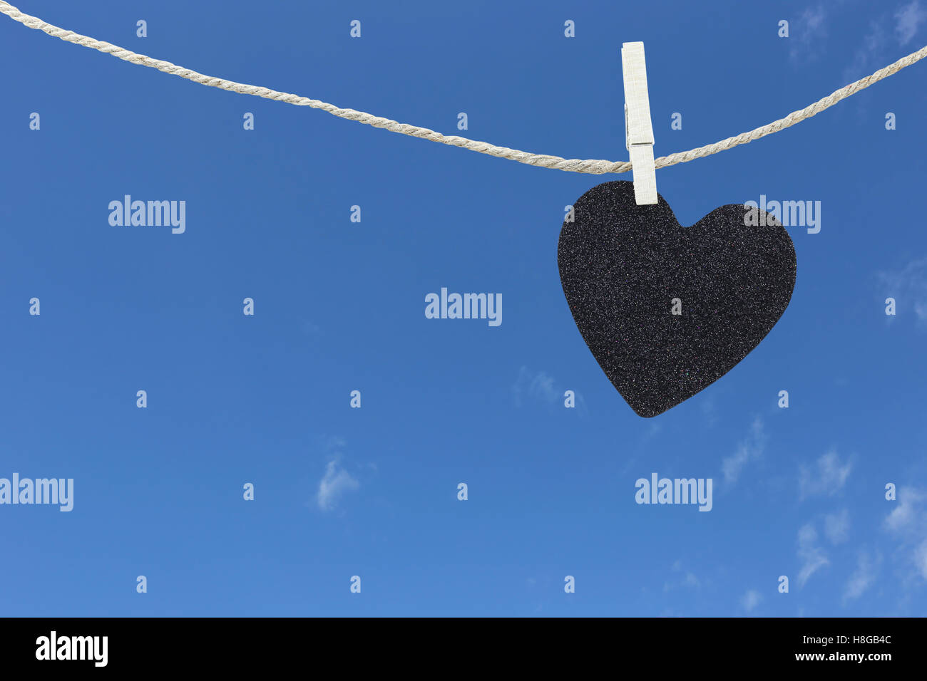 Black Heart hung on hemp rope on blue sky background and have copy ...