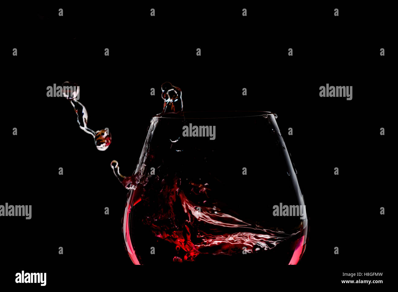 Splash of wine in the glass on dark background Stock Photo - Alamy